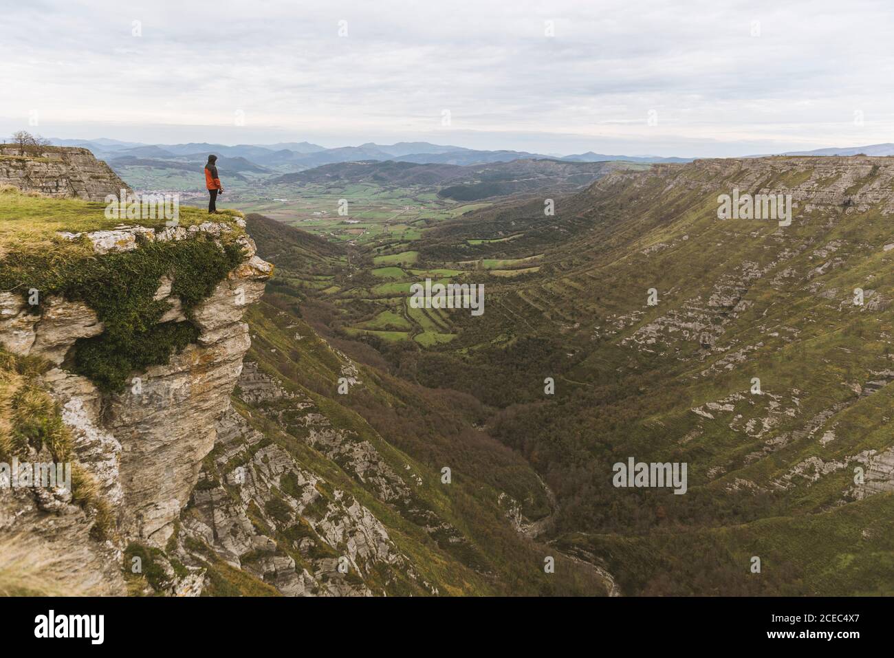 man standing on cliff near valley Stock Photo - Alamy