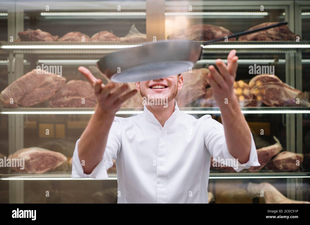 Chef cook in glasses and white gown throwing up frying pan working in ...
