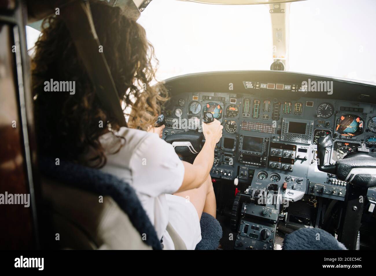 Back view of brunette Woman with curly hair sitting in cockpit and ...