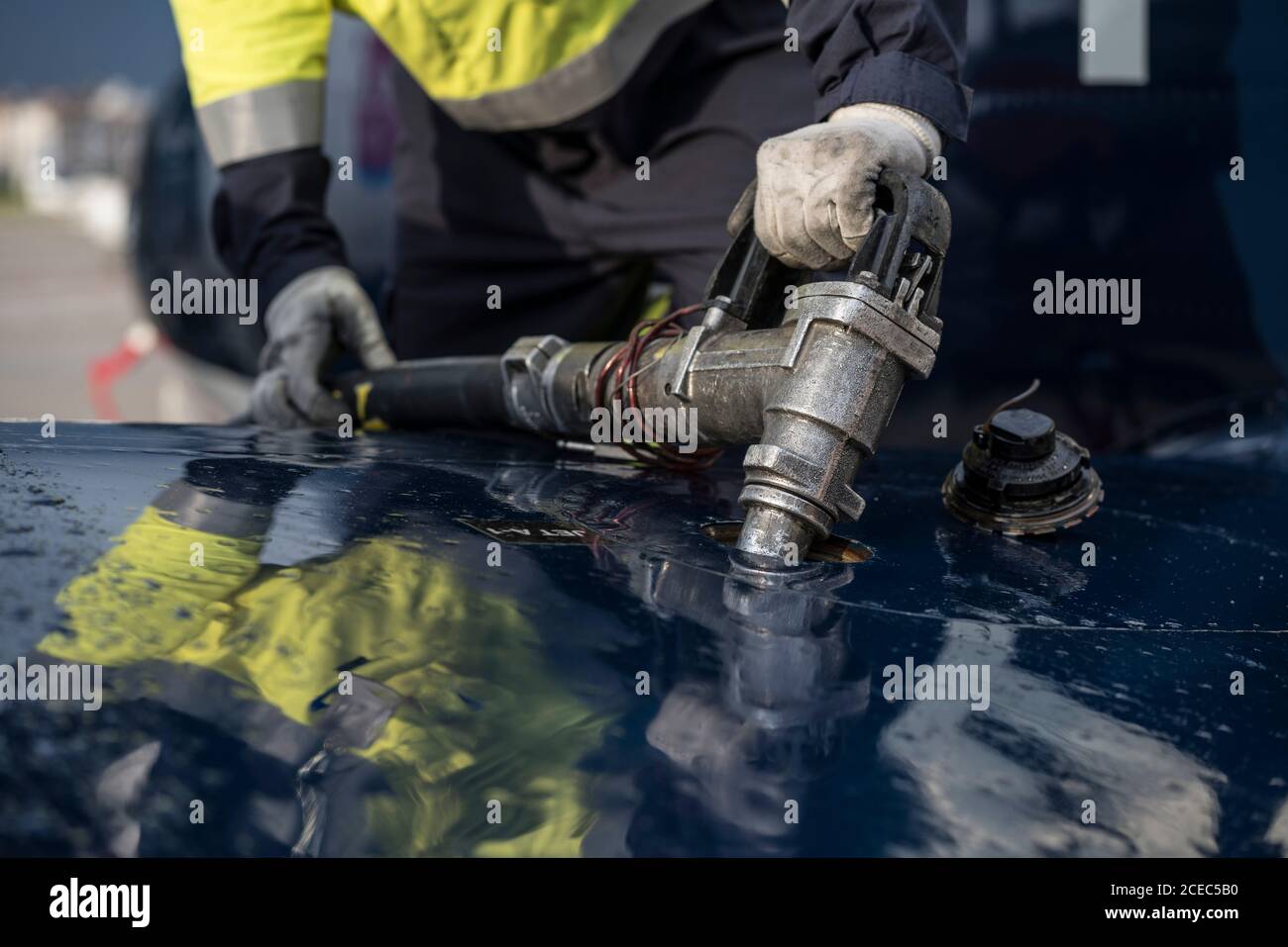 Crop man in uniform fueling modern plane while working on airfield ...