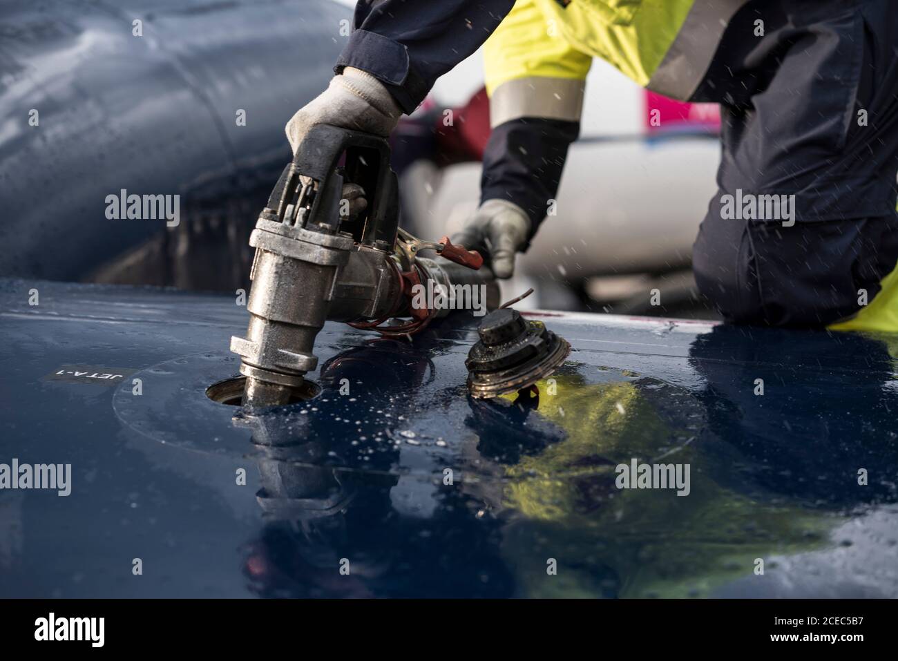 Crop man in uniform fueling modern plane while working on airfield ...