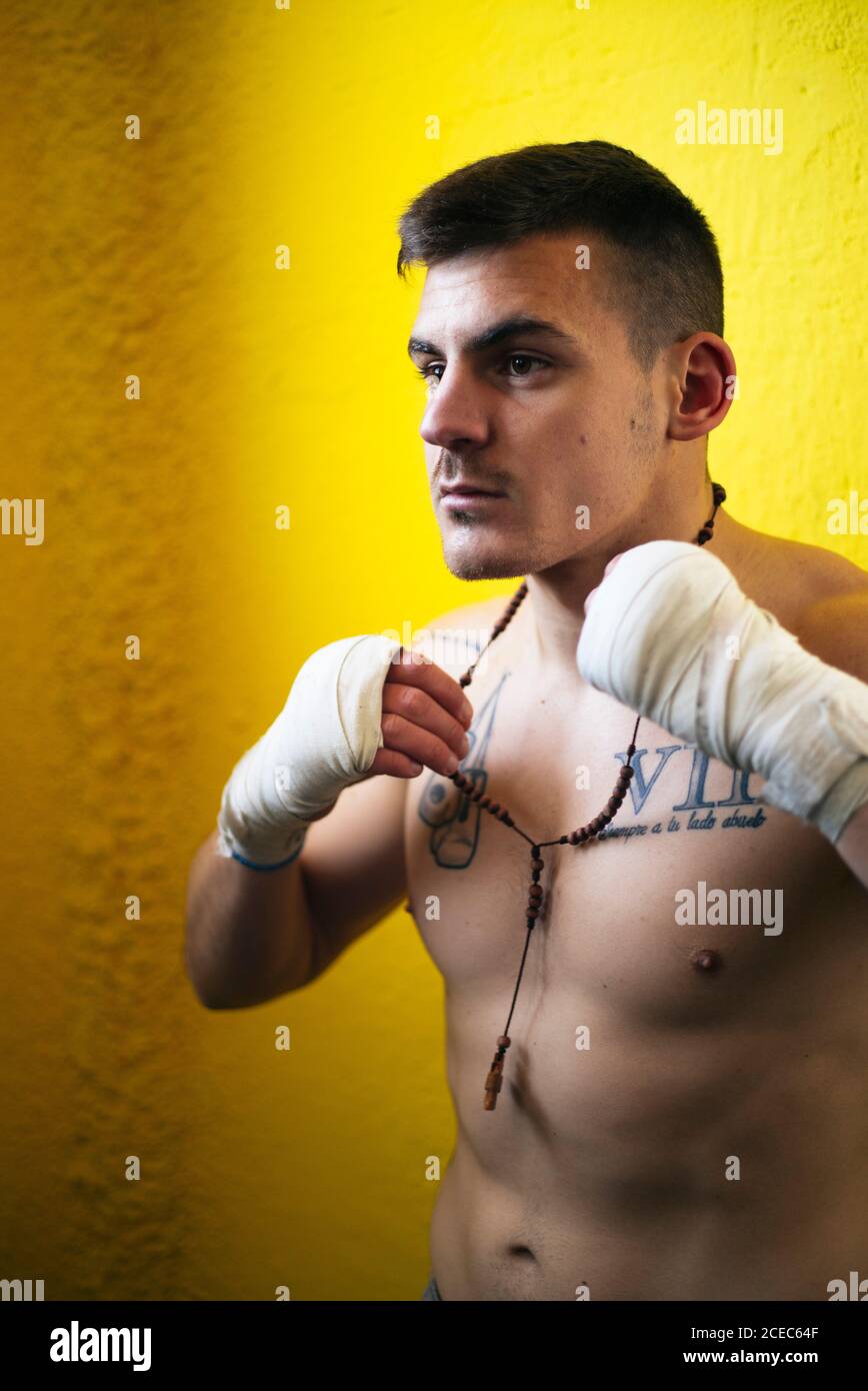 Muscular fighter with bandage arms putting on cross pendant Stock Photo ...