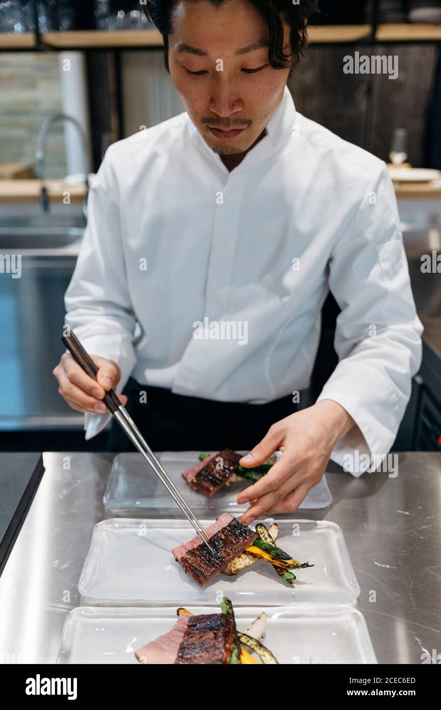 Chef cooking in restaurant prepares the dishes with chopsticks Stock ...