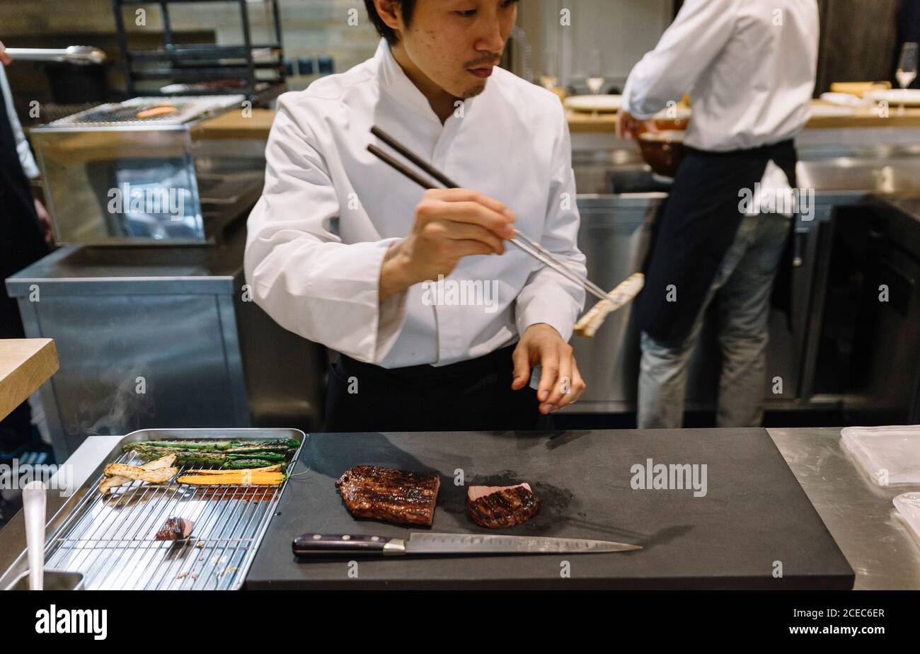 Chef cooking in restaurant prepares the dishes with chopsticks Stock ...