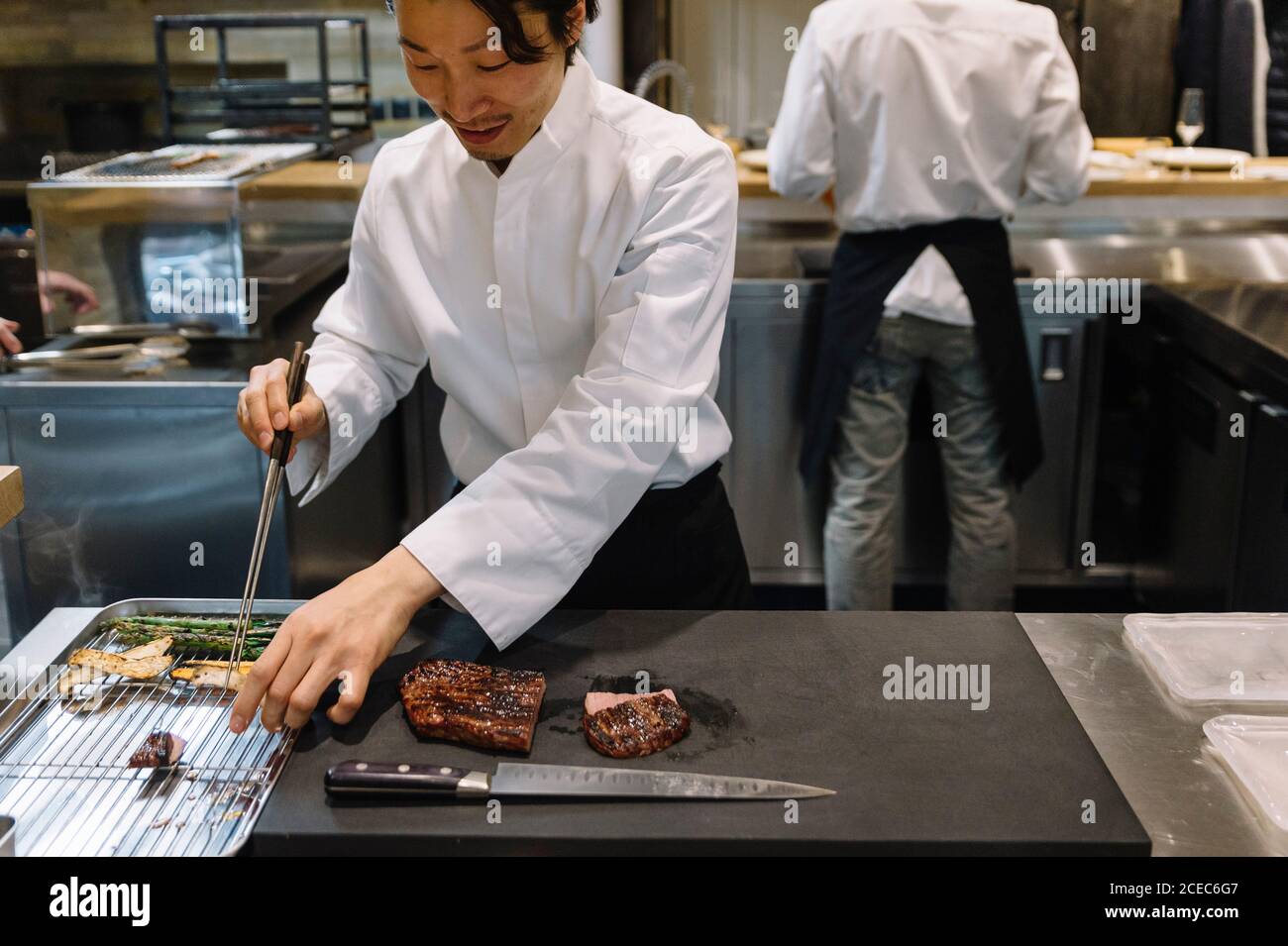Chef cooking in restaurant prepares the dishes with chopsticks Stock ...