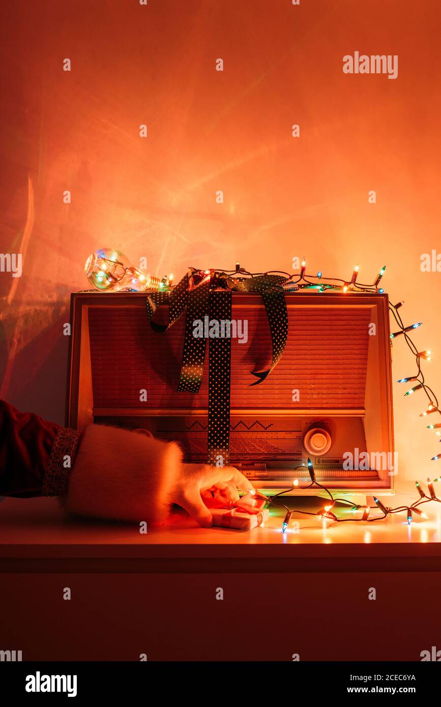 Hand of anonymous Santa Claus putting small present on cabinet near ...