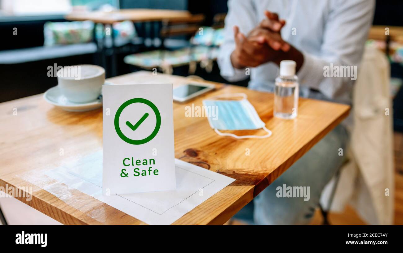 Clean and safe sign with man disinfecting his hands in background Stock ...