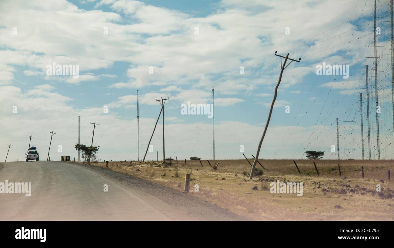 Car riding along road in desert with falling electric poles Stock Photo ...