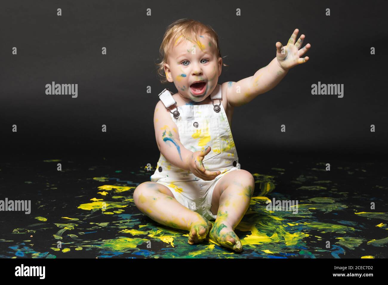 Adorable dirty little boy sitting and playing with yellow and blue ...
