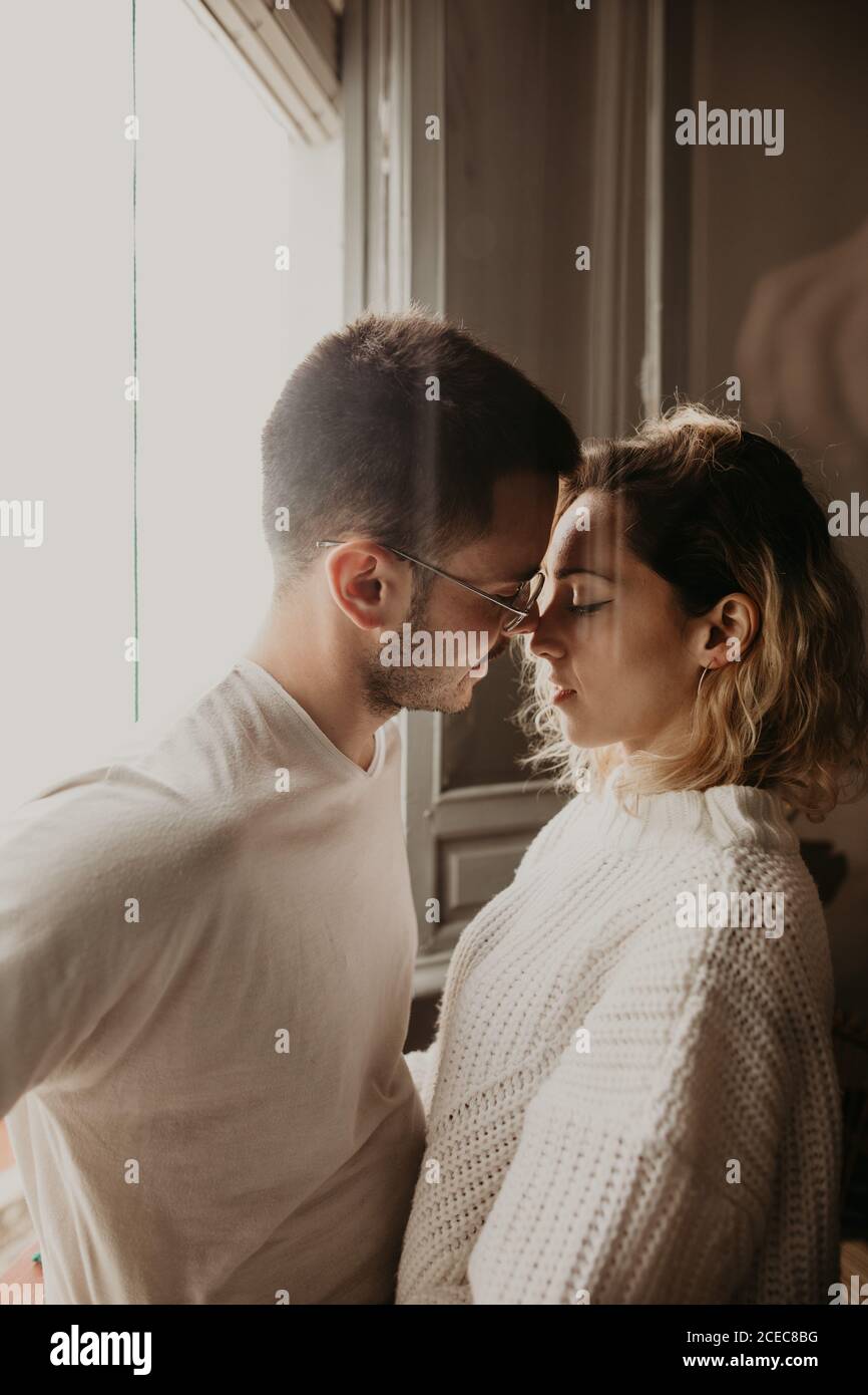 Side view of couple embracing and bonding at home Stock Photo - Alamy