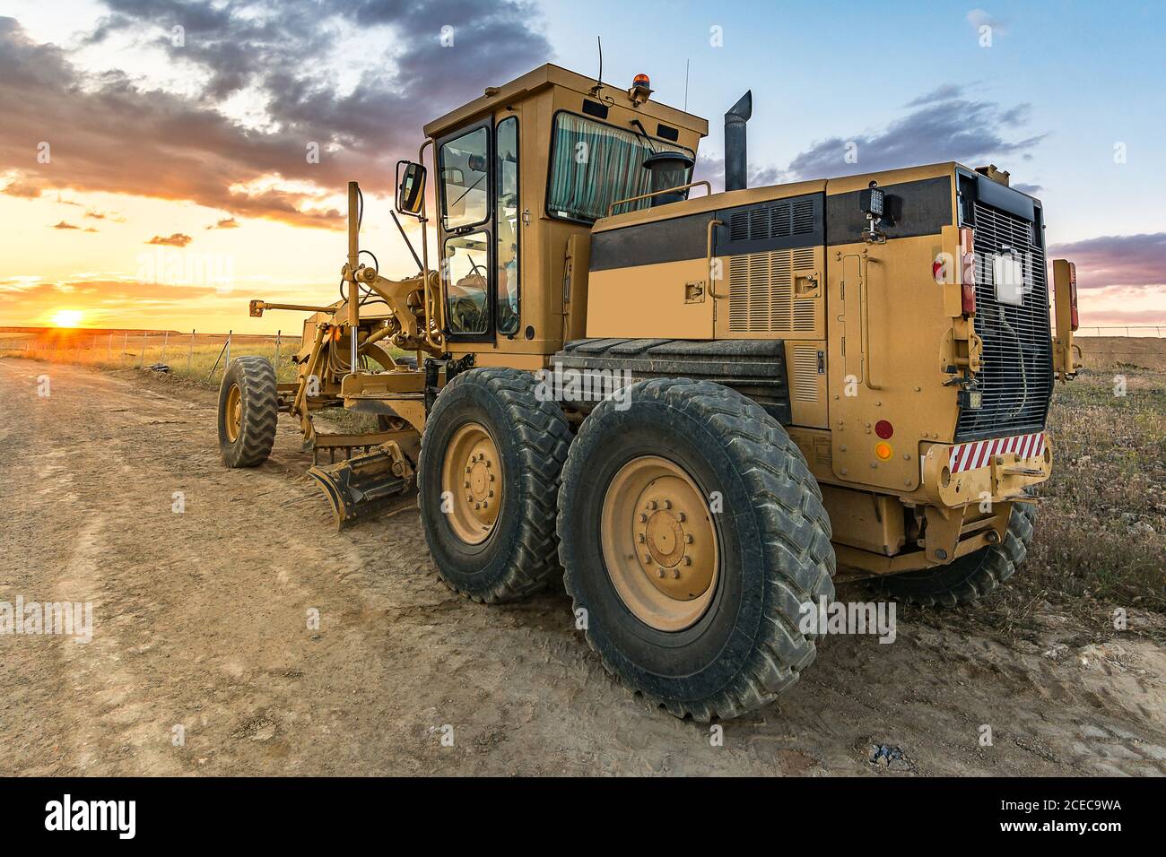 Bulldozer on roadside of unpaved highway Stock Photo - Alamy