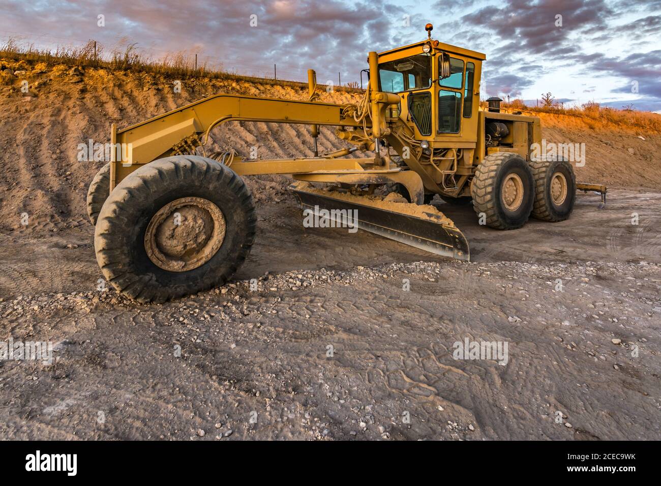 Bulldozer on roadside of unpaved highway Stock Photo - Alamy
