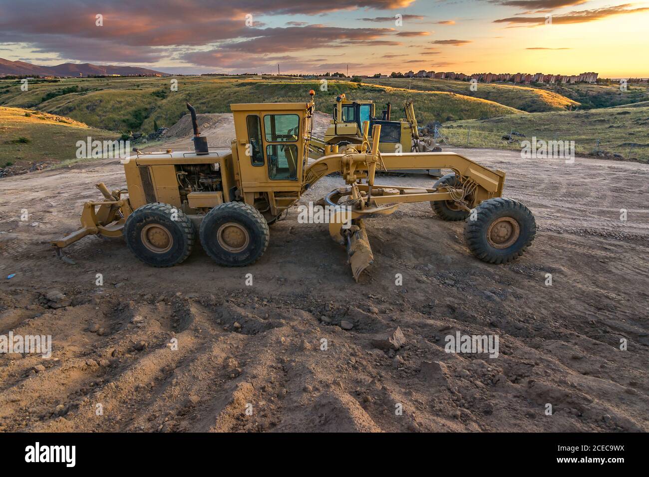 Bulldozer on roadside of unpaved highway Stock Photo - Alamy