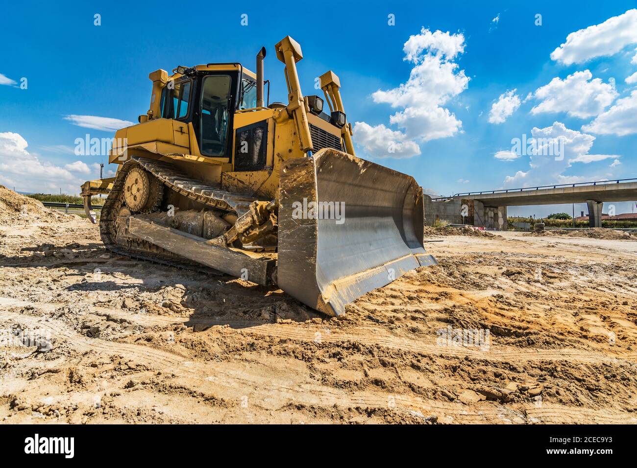 Bulldozer on roadside of unpaved highway Stock Photo - Alamy