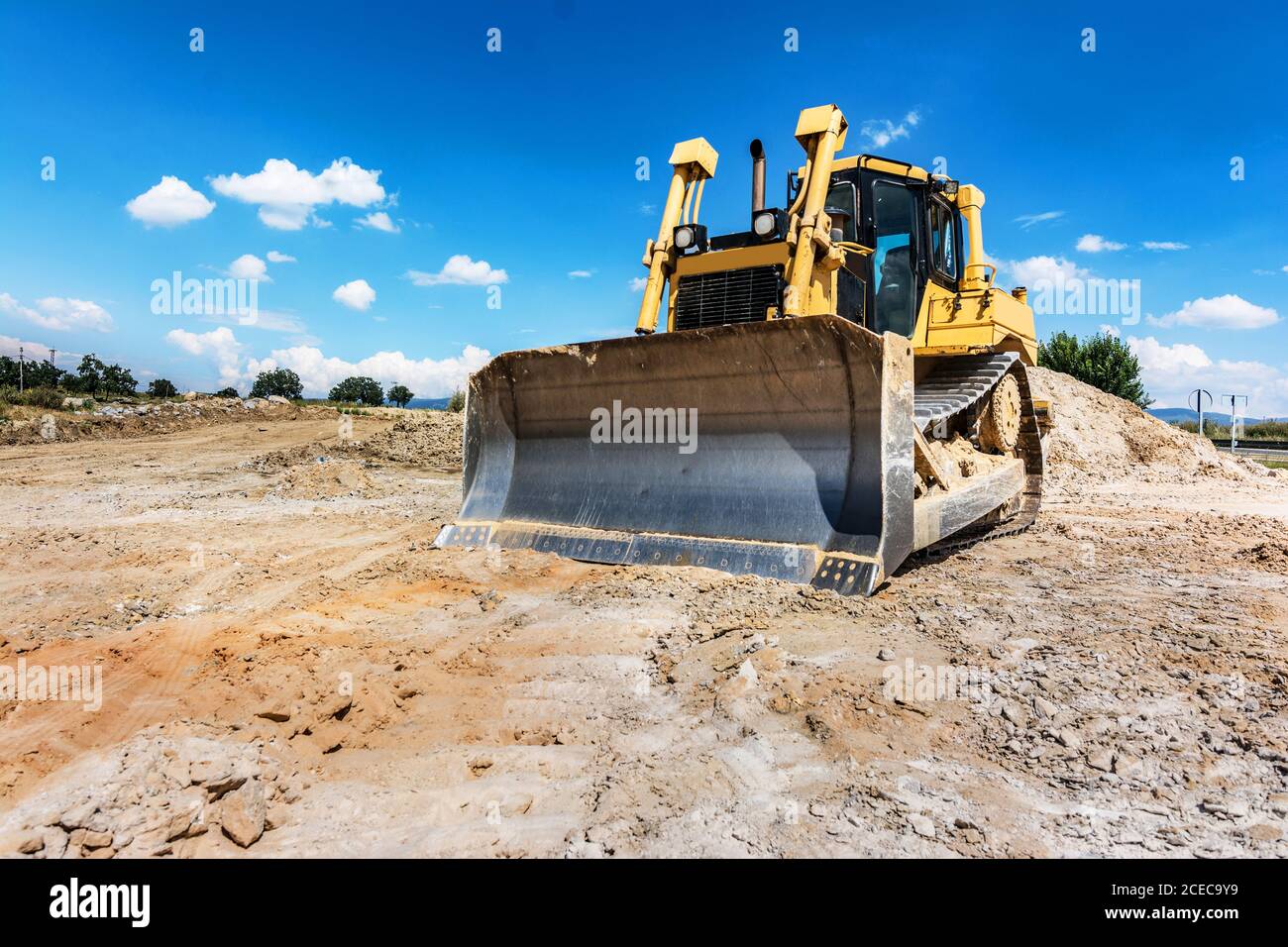 Bulldozer on roadside of unpaved highway Stock Photo - Alamy