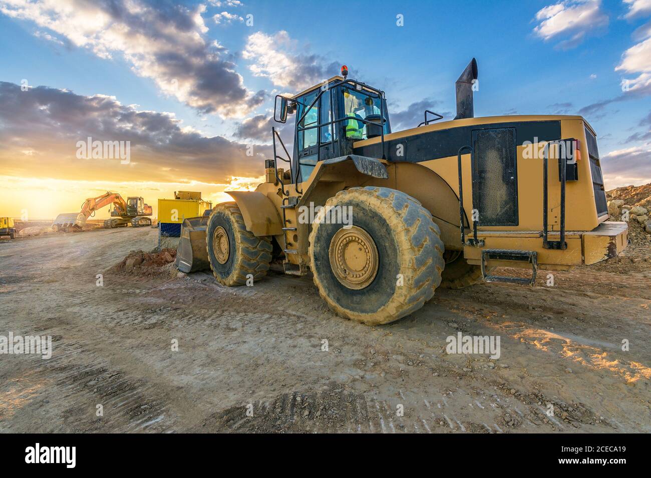Bulldozer on roadside of unpaved highway Stock Photo - Alamy