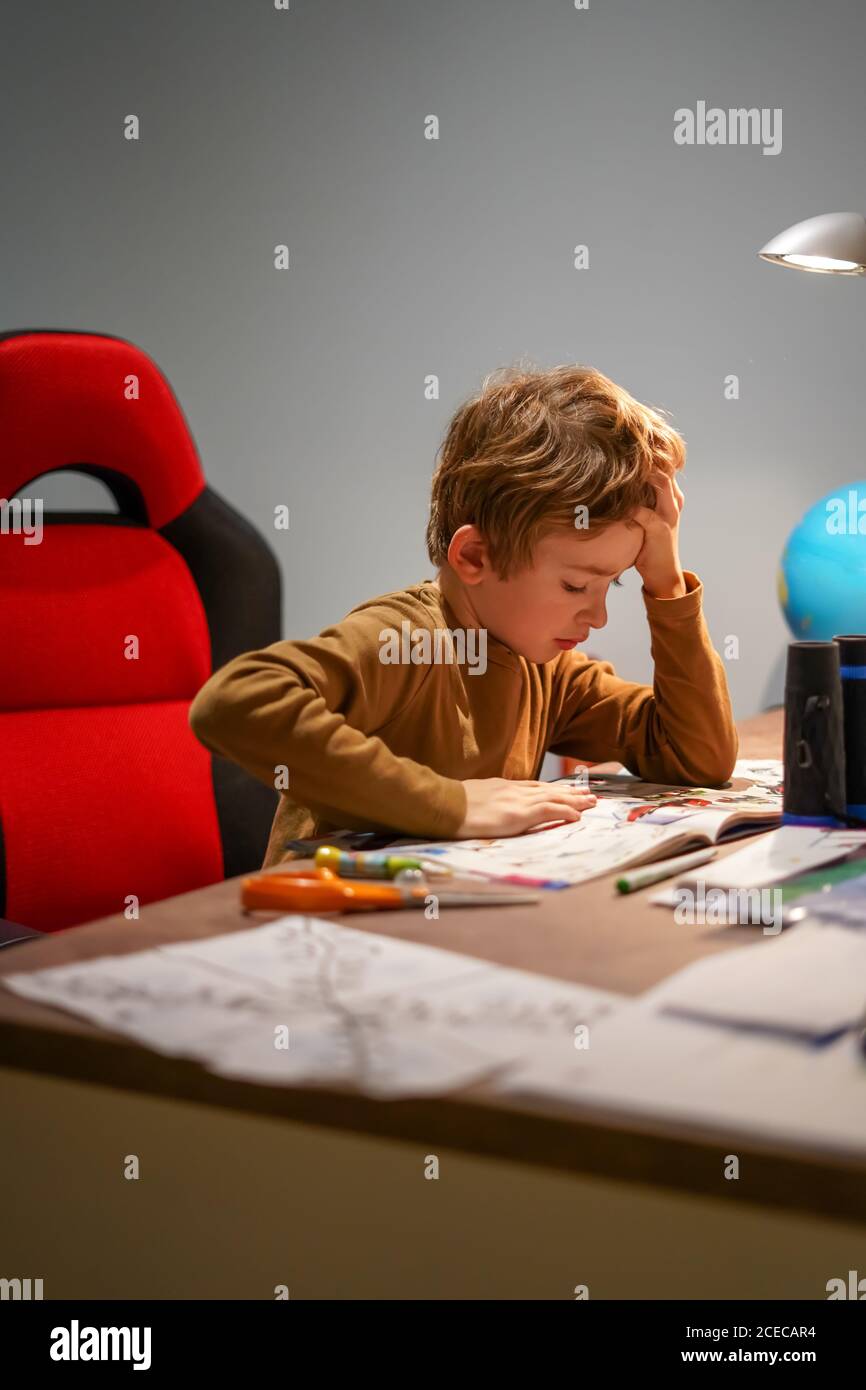 Portrait school boy siting on table doing homework. Elementary school ...