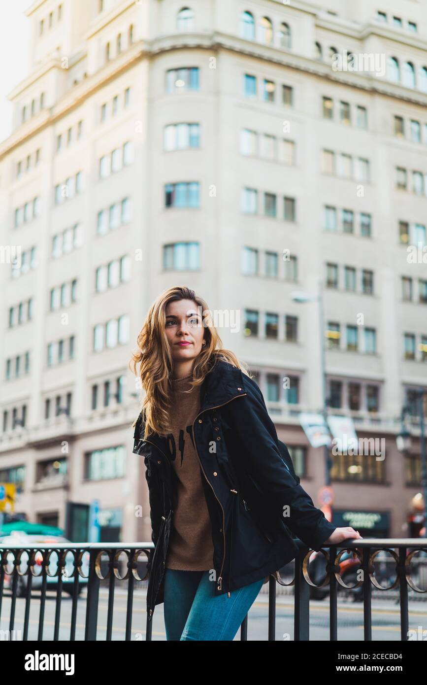 Pretty Woman leaning on handrail in city Stock Photo - Alamy