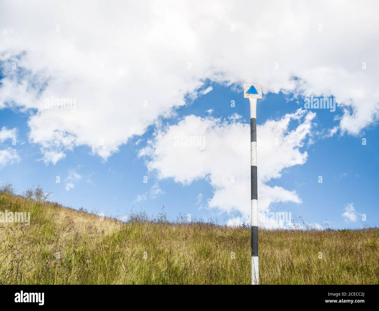 Blue triangle hiking trail mark on a pole with the blue sky and white ...