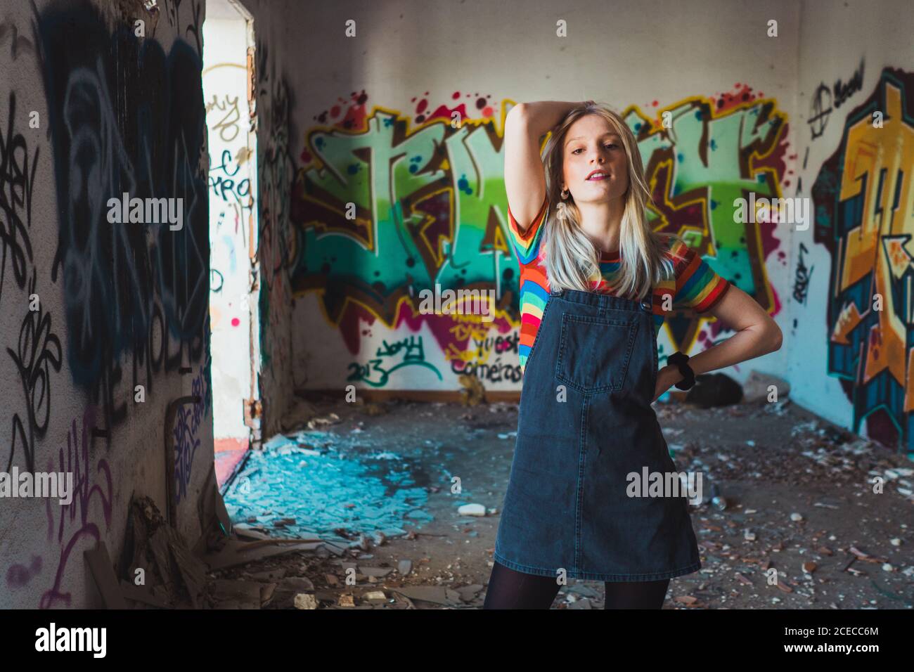 Young trendy blond model standing in abandoned building with walls in ...