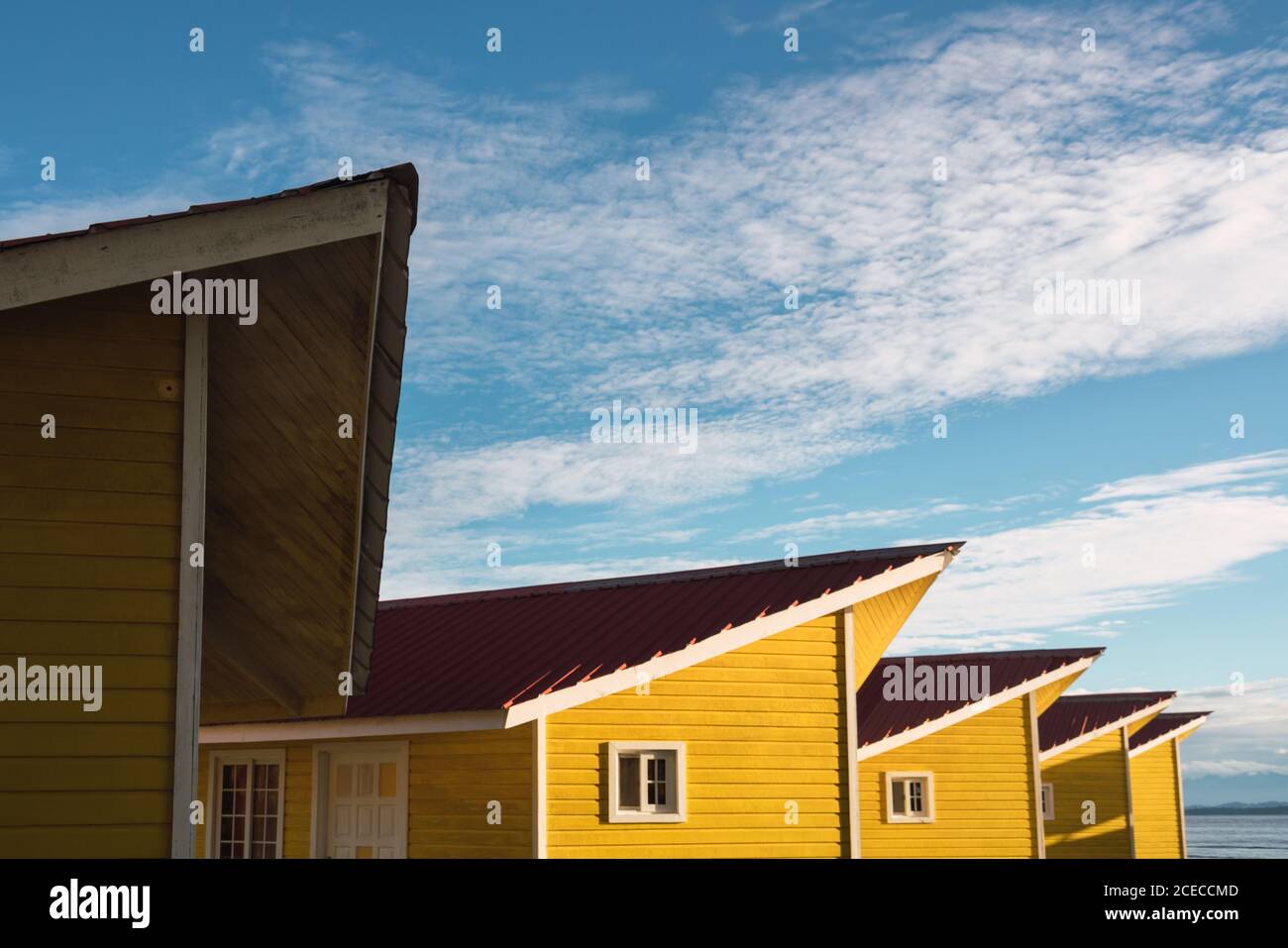 Perspective view of bright yellow remote houses in row under blue sky ...