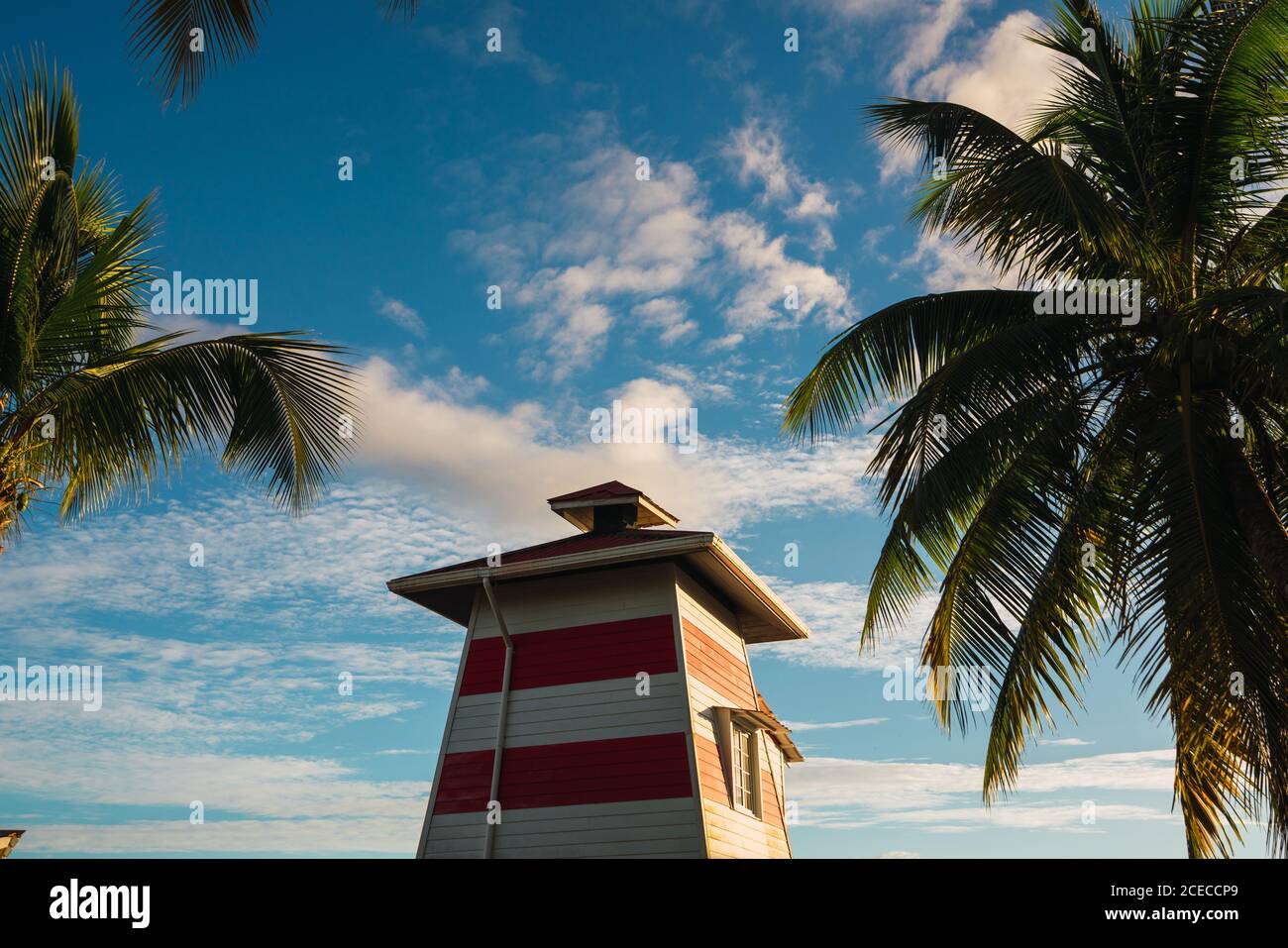 Tropical seashore with small wooden lighthouse on pier with yellow ...