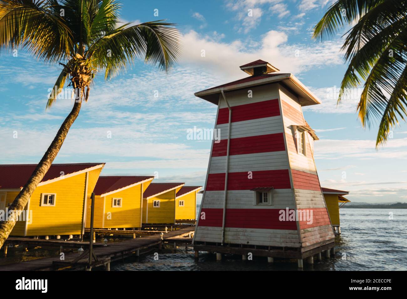 Tropical seashore with small wooden lighthouse on pier with yellow ...