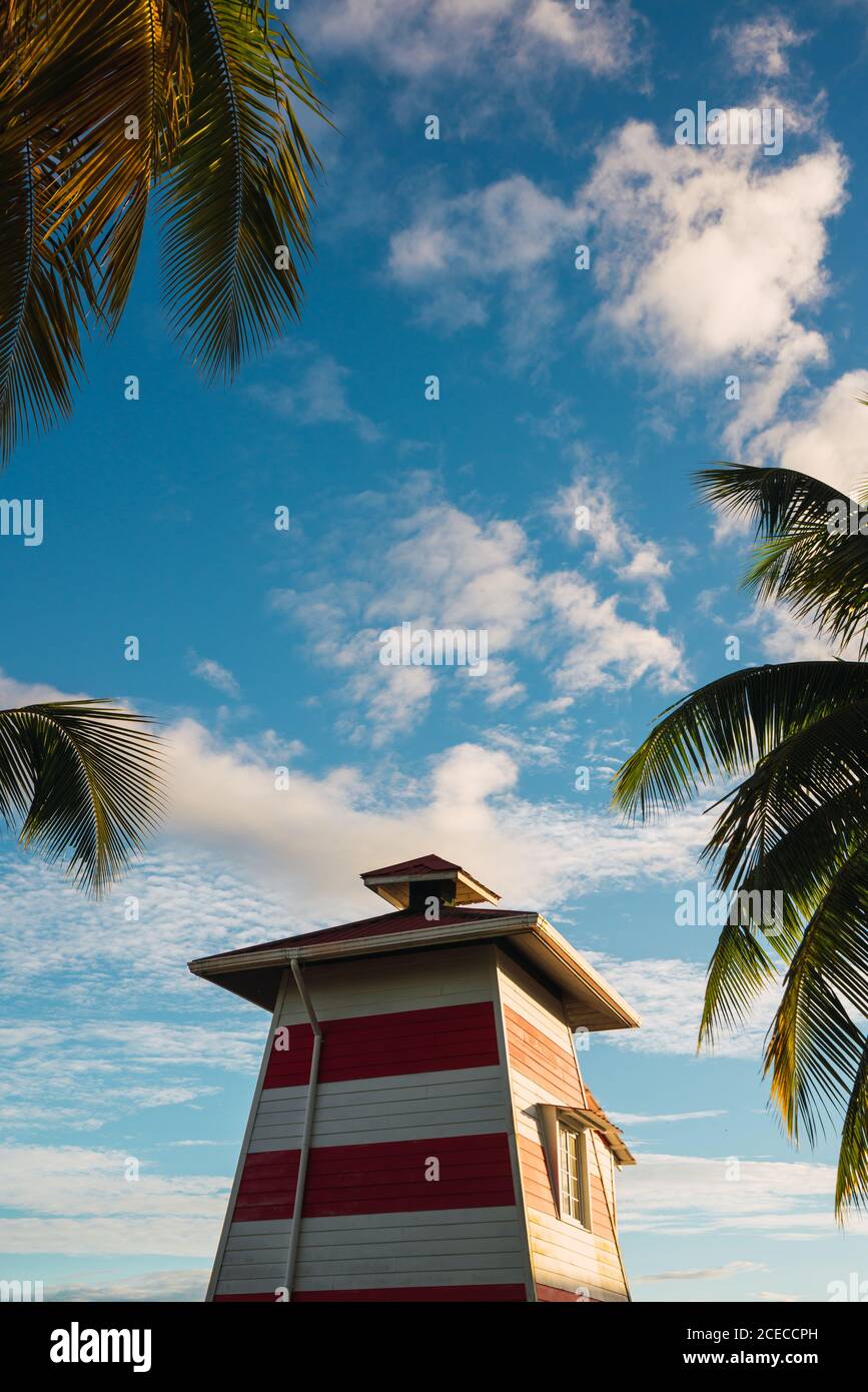 Tropical seashore with small wooden lighthouse on pier with yellow ...