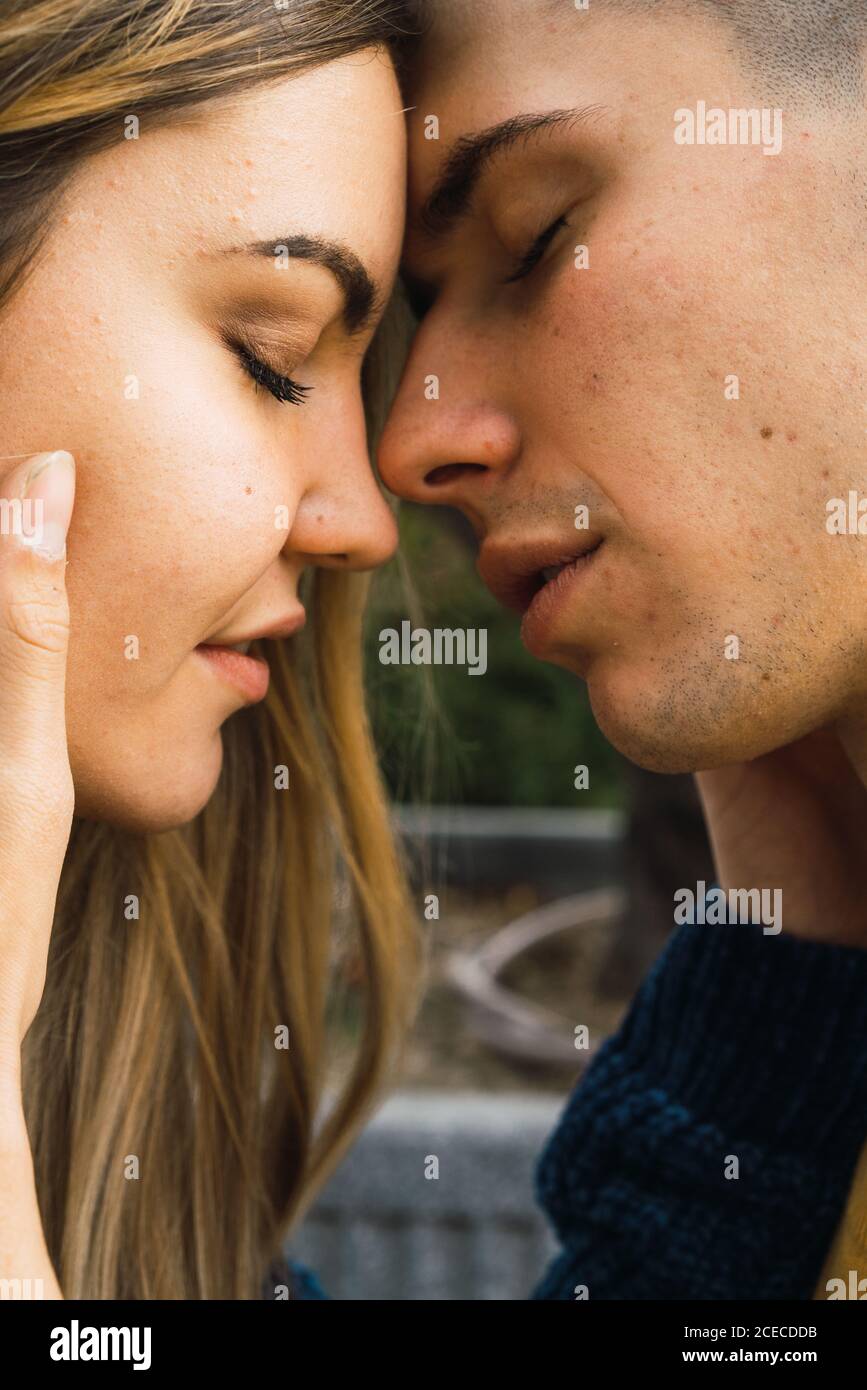 Side view of young loving people caressing each other and kissing with ...