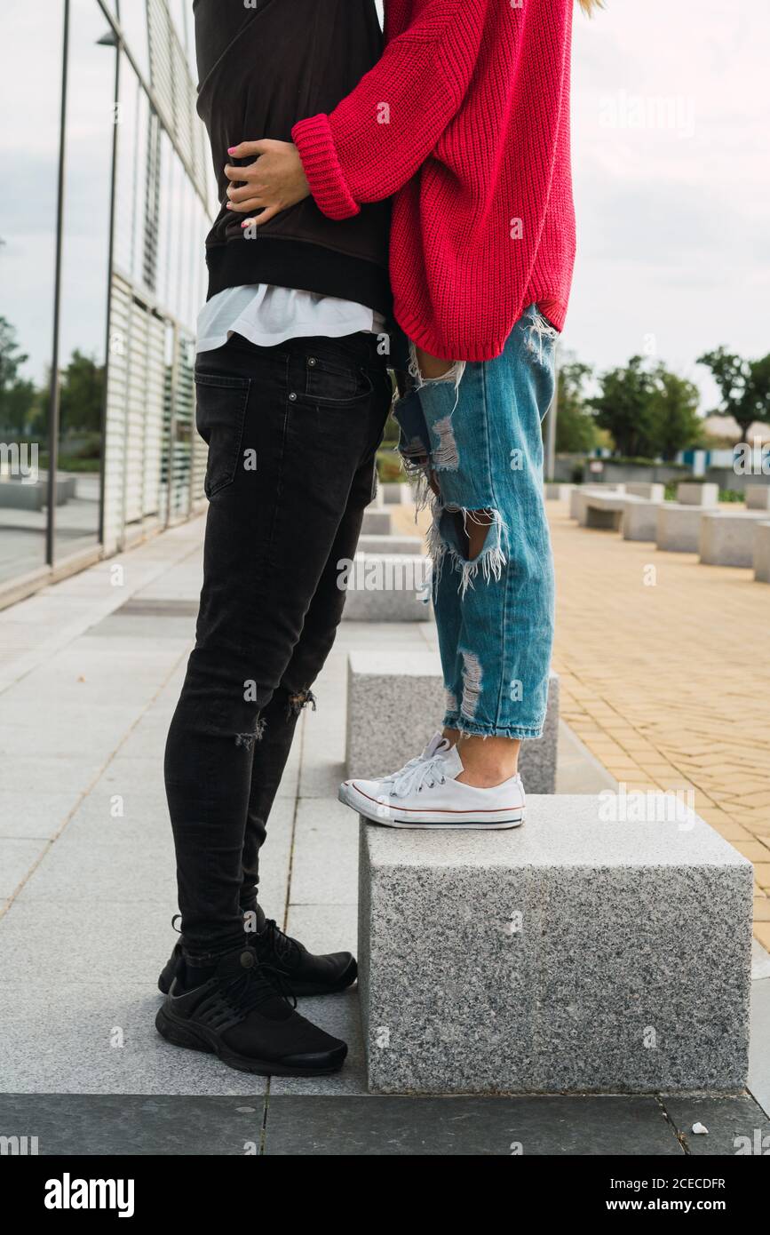 faceless shot of stylish Woman on fence kissing man standing near on ...