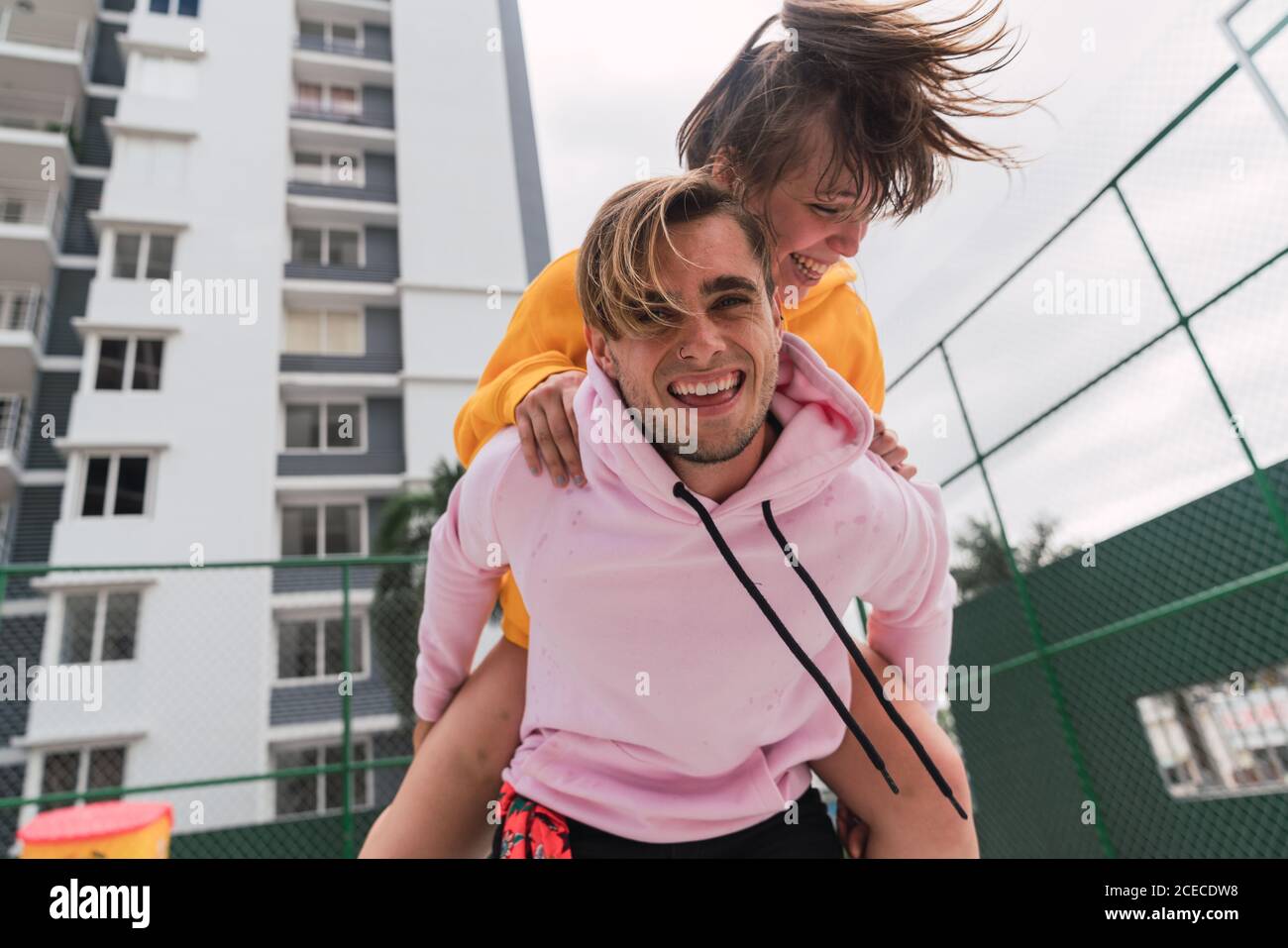 Handsome young guy laughing and giving piggyback ride to excited ...