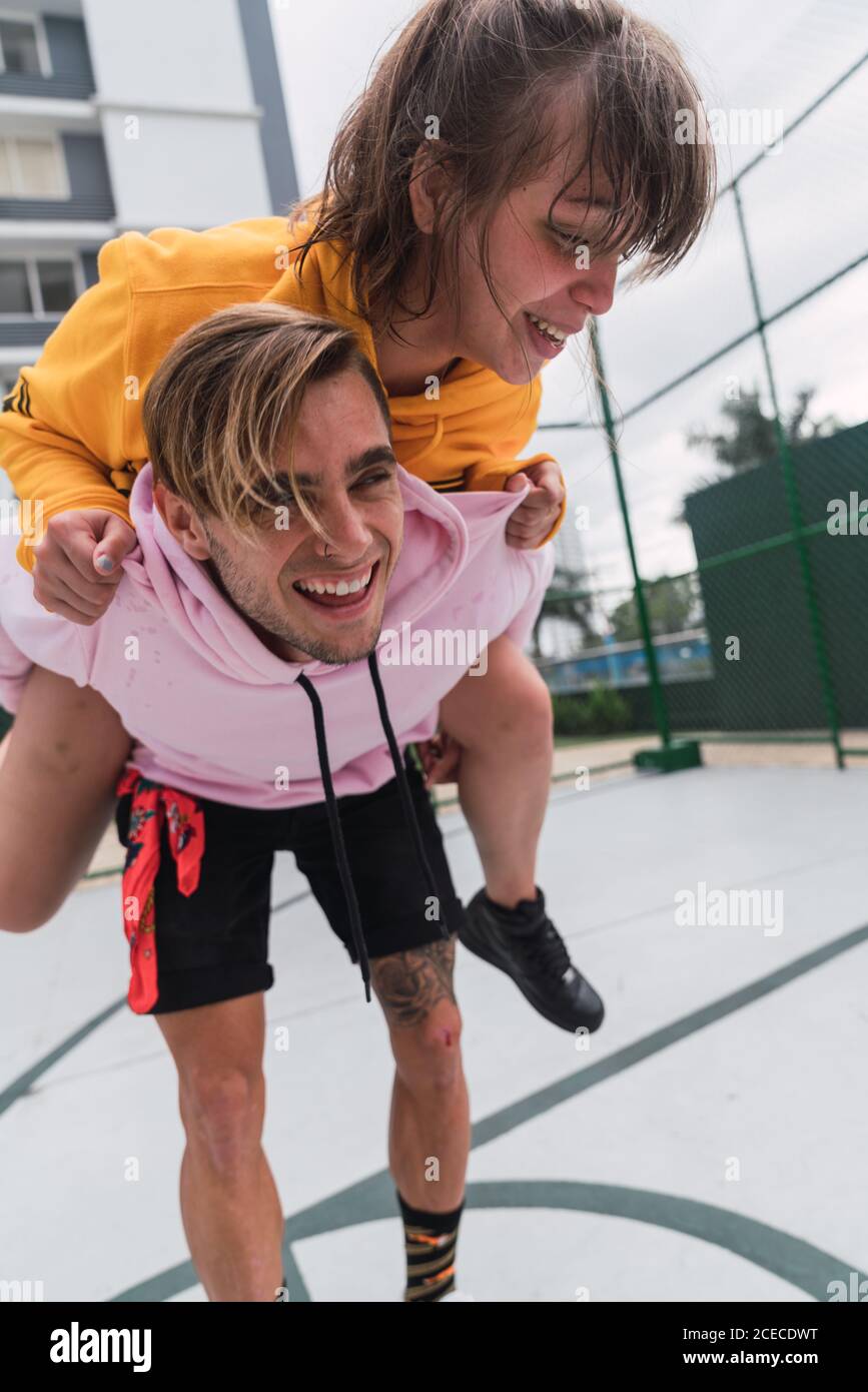 Handsome young guy laughing and giving piggyback ride to excited ...