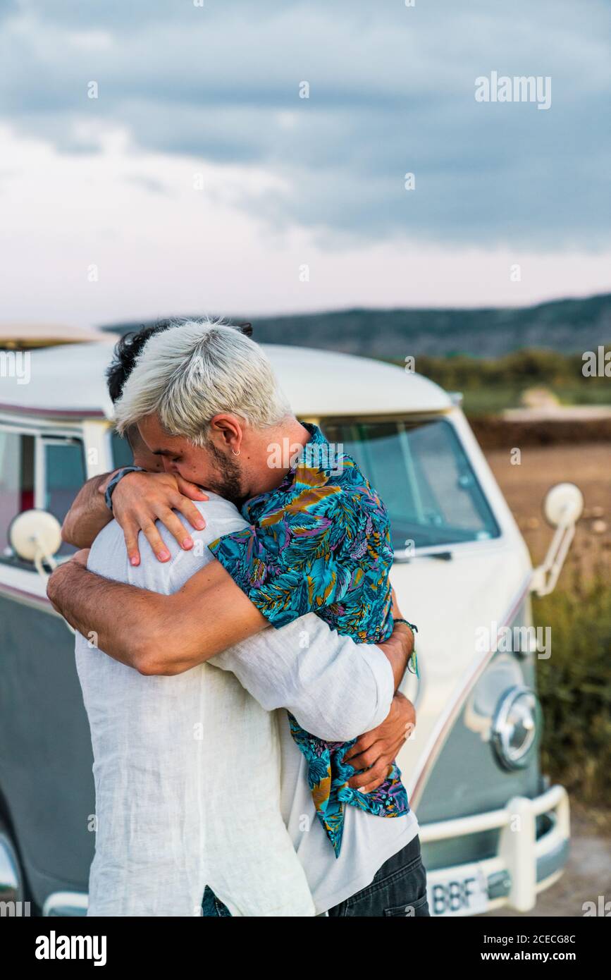 Side view of two anonymous guys hugging passionately while standing in ...