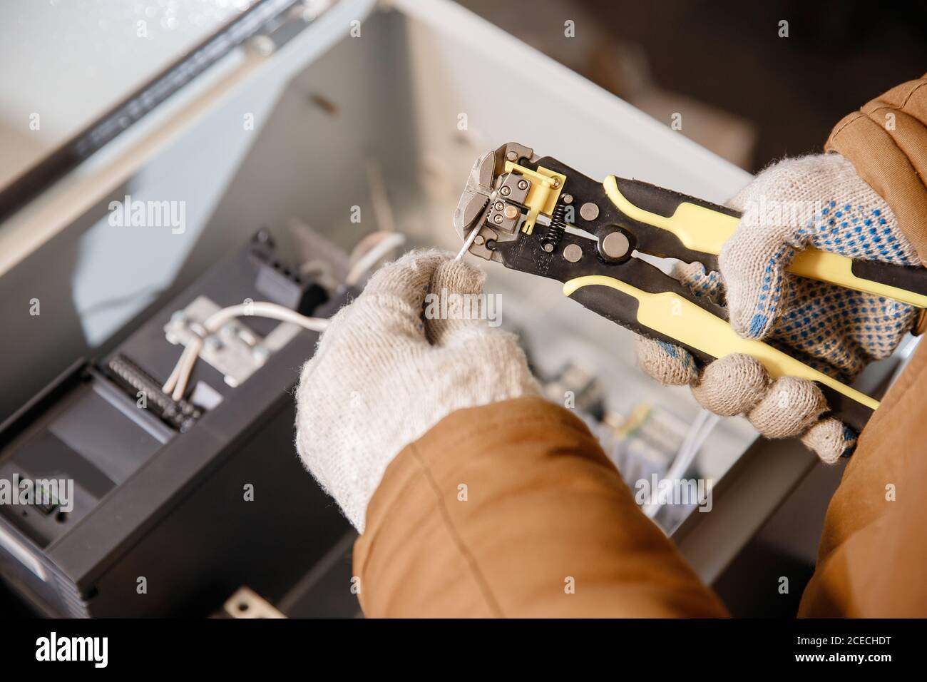 Master electrician with professional tool for removing insulation from ...