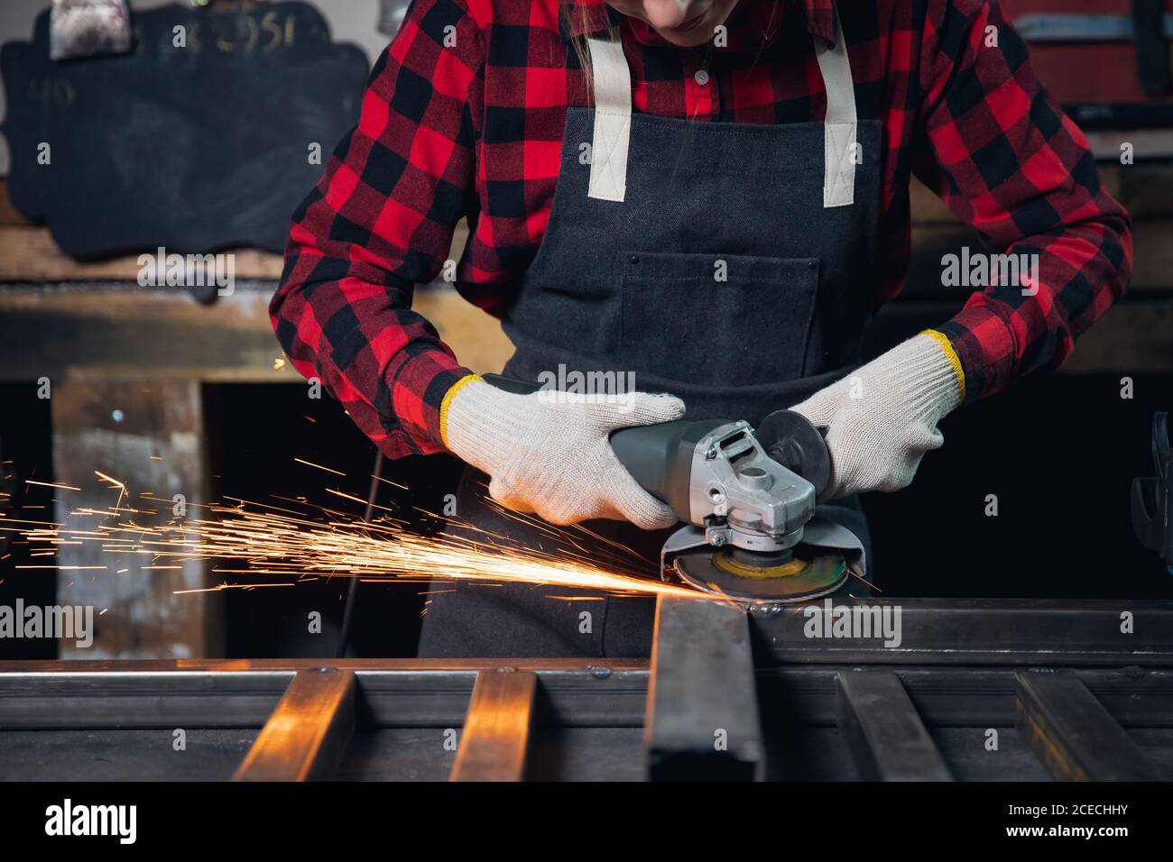 Worker hand with electric wheel grinding on steel structure in factory ...