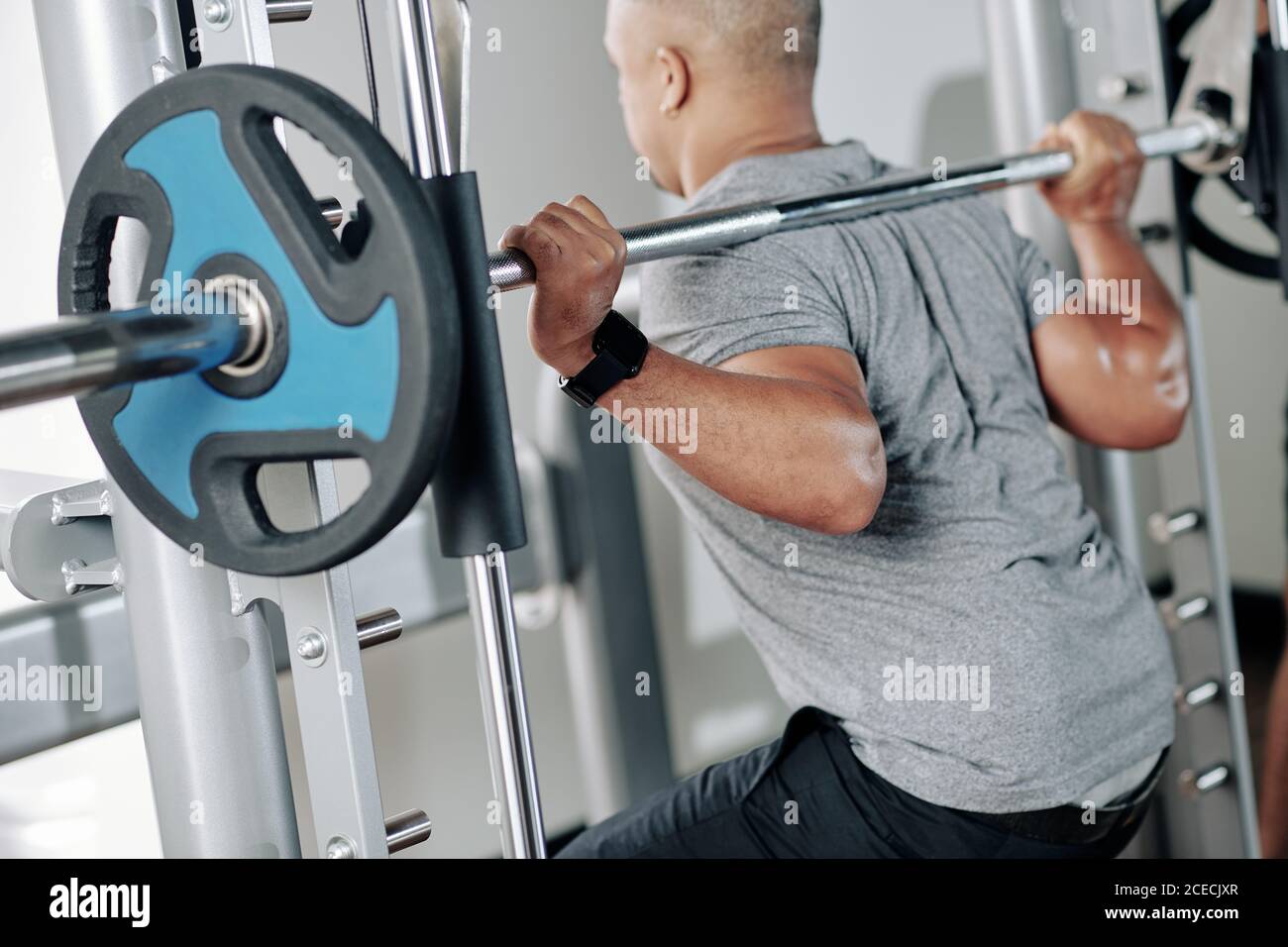 Mature muscular man doing squats with large barbell with heavy weight ...