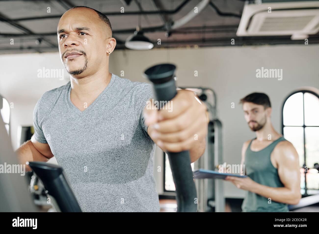 Man walking on elliptical machine Stock Photo - Alamy