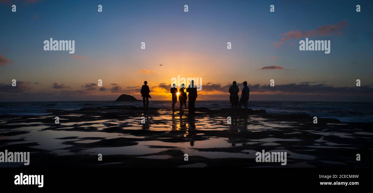 Silhouette image of people enjoying sunset at Muriwai beach, Waitakere ...
