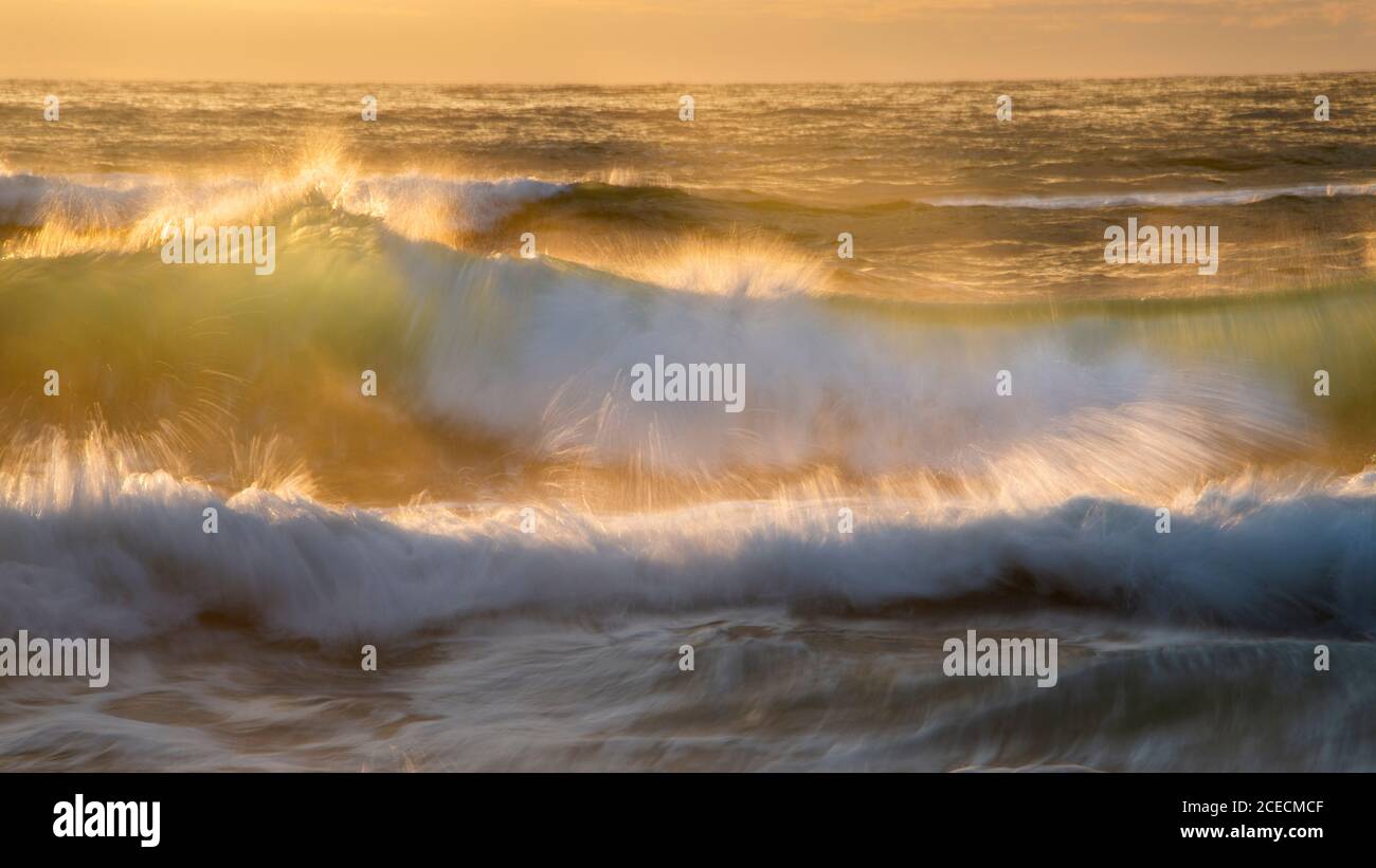 Crashing waves back lit by the setting sun. Image taken using slow ...