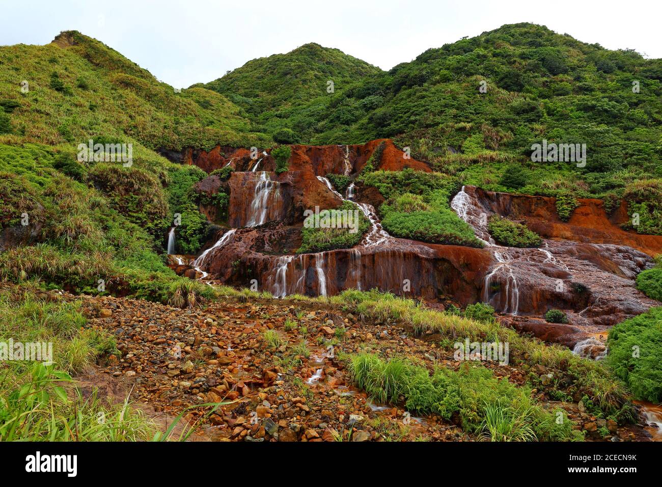 Golden Waterfall flowing over rust-colored rocks & soil due to minerals ...