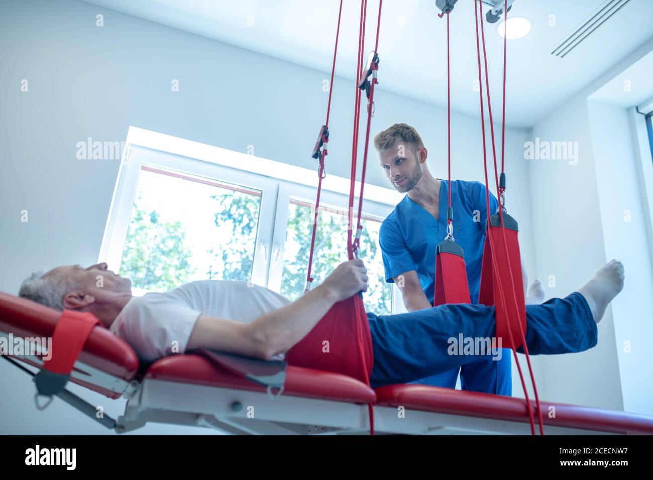 Rehabilitation therapist and patient on couch with raised legs Stock ...