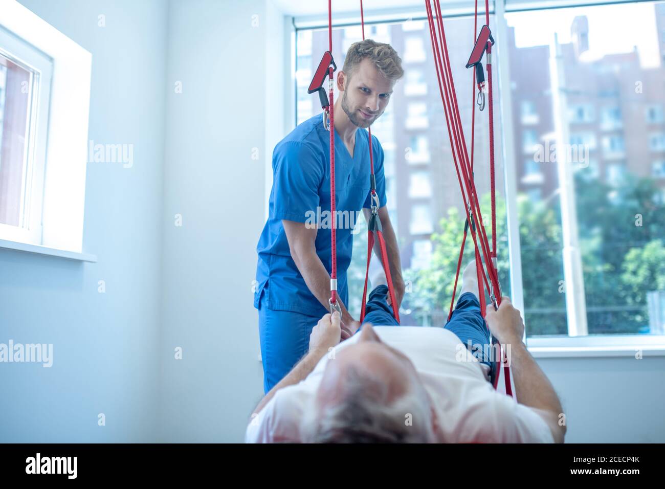 Rehabilitator lifting the leg of lying patient Stock Photo - Alamy
