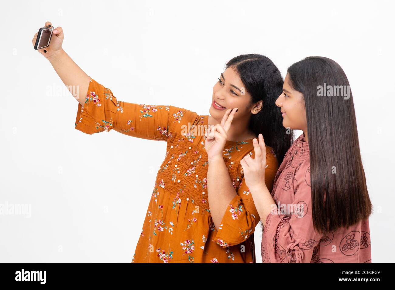 Two young Indian girls taking photo on their smart phone. Cute ...
