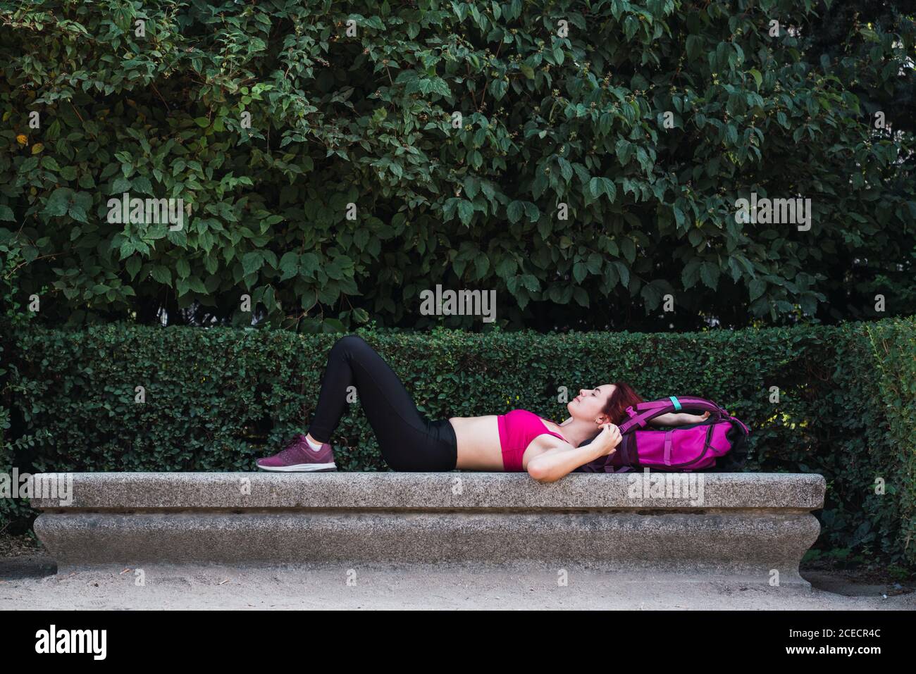 Side view of attractive Woman in sportswear having rest on stone bench ...
