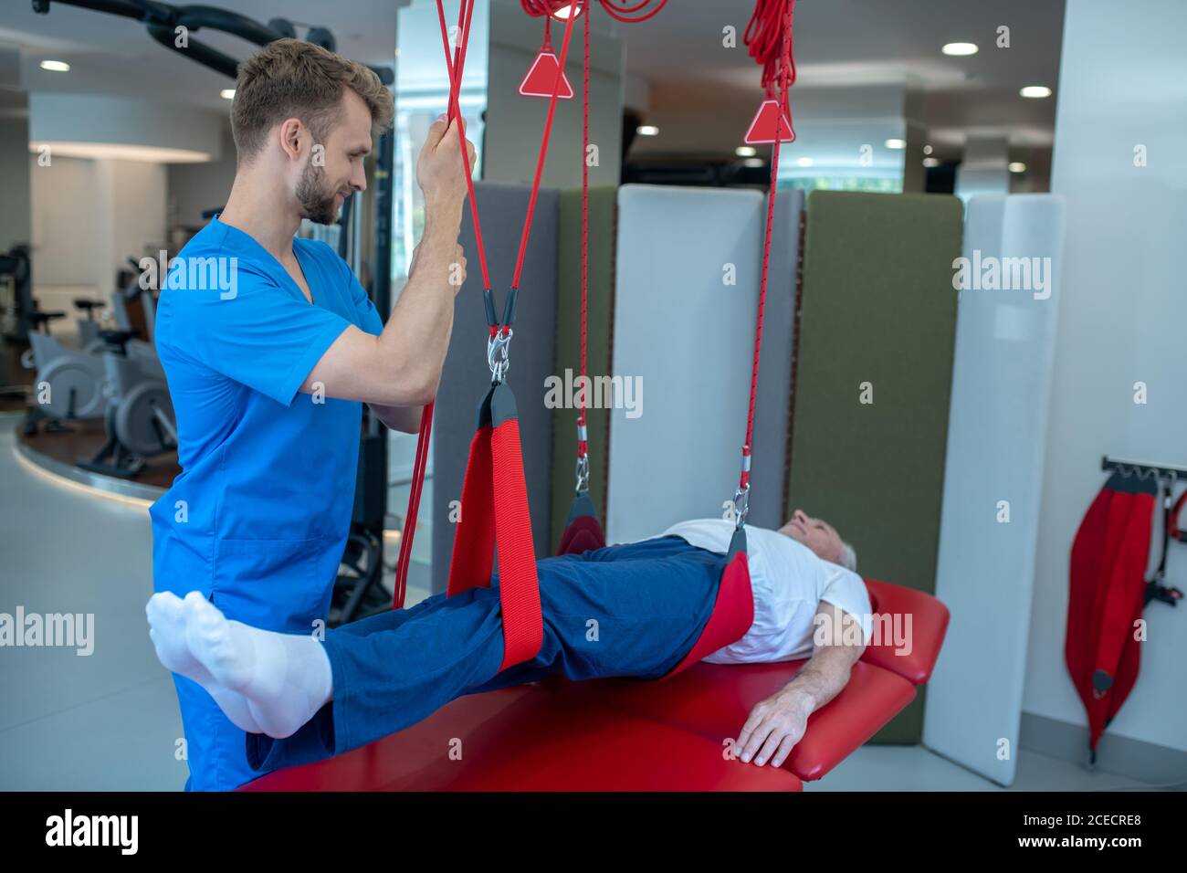 Rehabilitation therapist lifting up on straps of patients leg Stock ...
