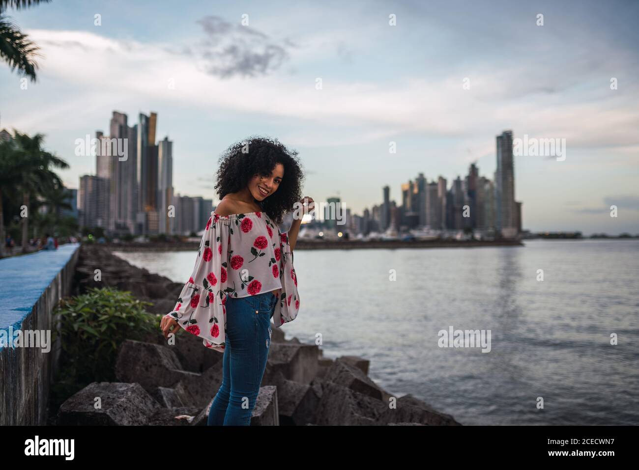 Side view of charming black Woman on rocks of Panama city seafront ...