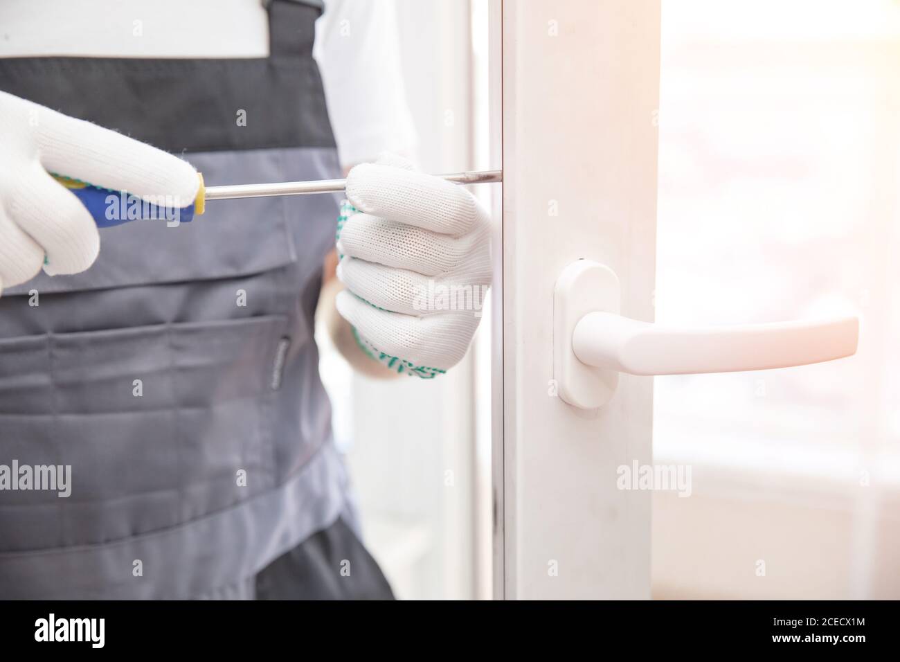 Worker man installs plastic windows and doors with double-glazed white ...