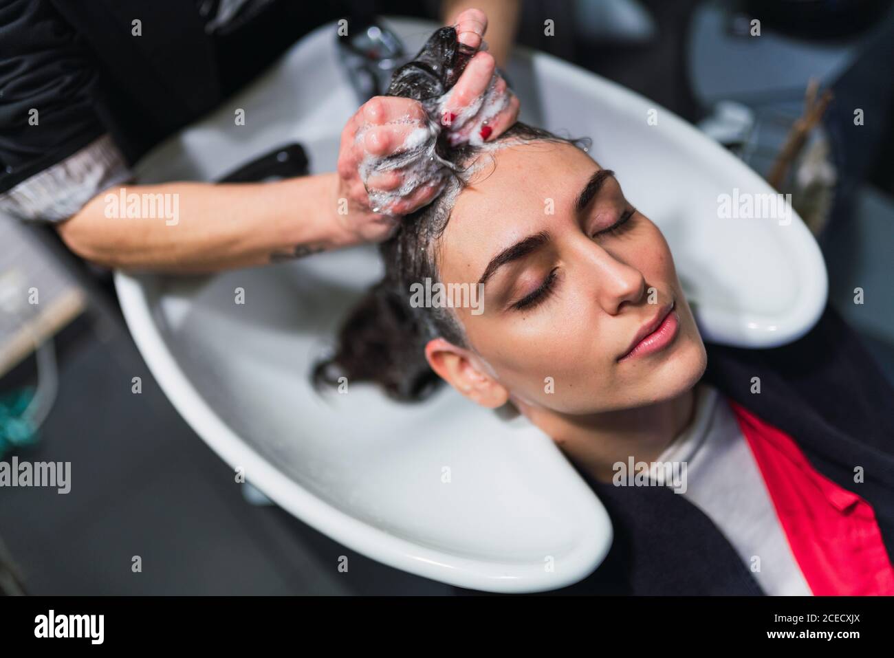 From above Woman washing hairs to attractive lady with closed eyes in ...