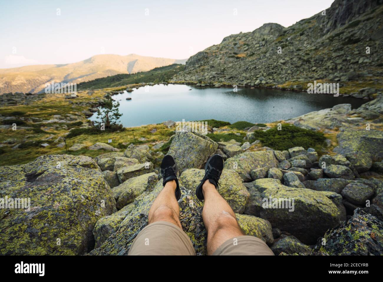 Crop man sitting on shore of lake Stock Photo - Alamy