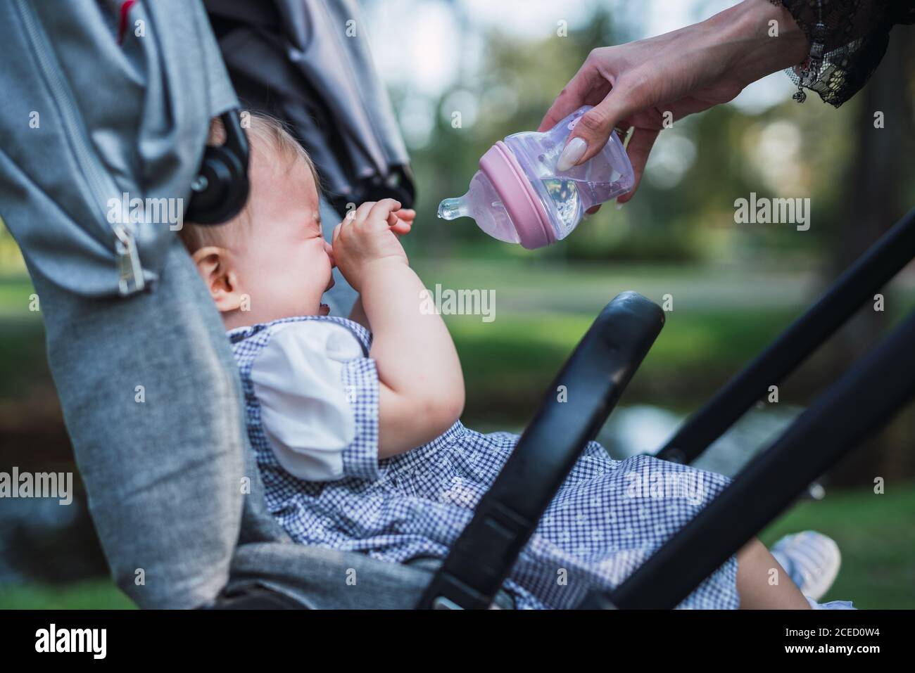Hand of anonymous mother holding bottle of water and trying to comfort ...